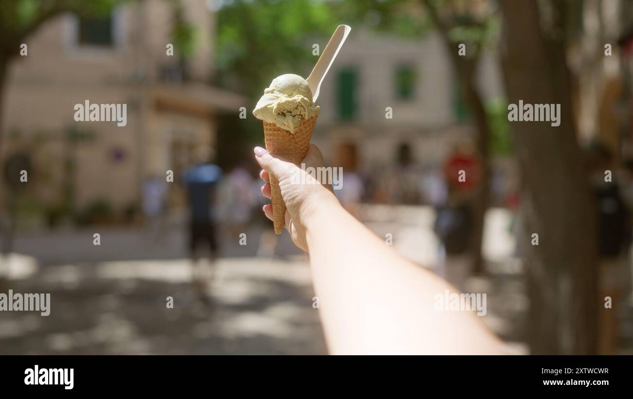 Woman holding ice cream cone outdoors in sunny street with blurred ...