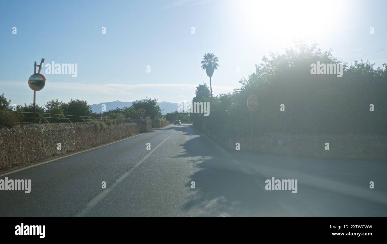 Road leading through a scenic sunny landscape with a stop sign and a ...