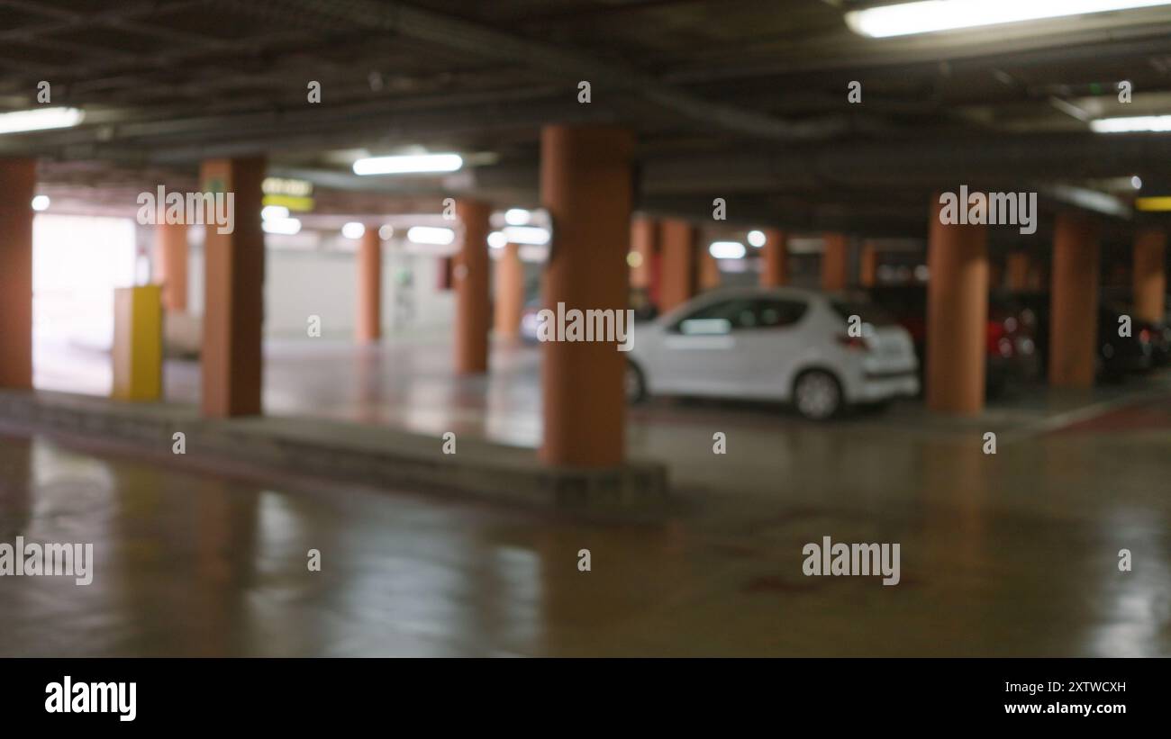 Blurred background of an indoor parking area with defocused cars and ...