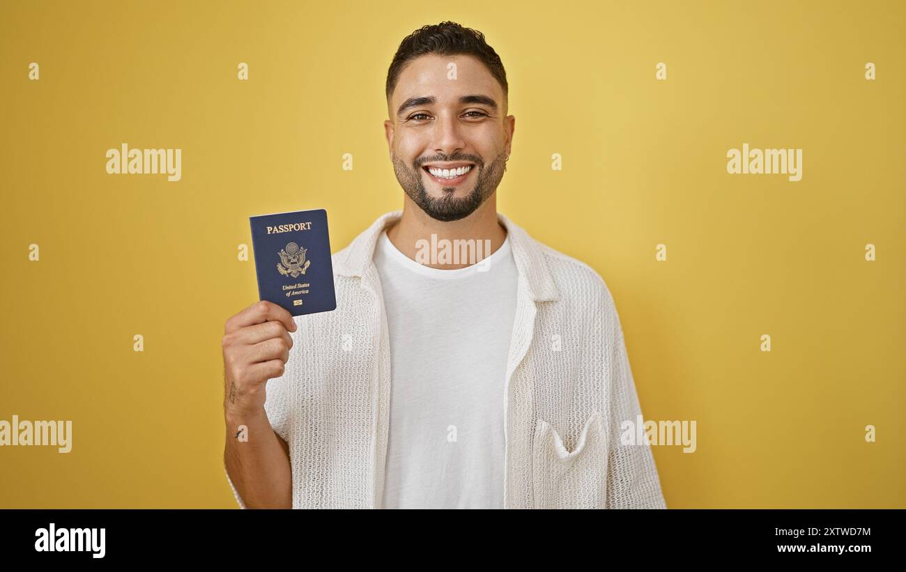A cheerful young man with a beard presenting a us passport against a ...