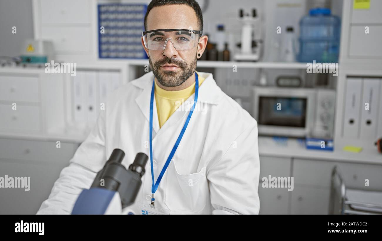 Handsome hispanic scientist with a beard engages with a microscope in a ...