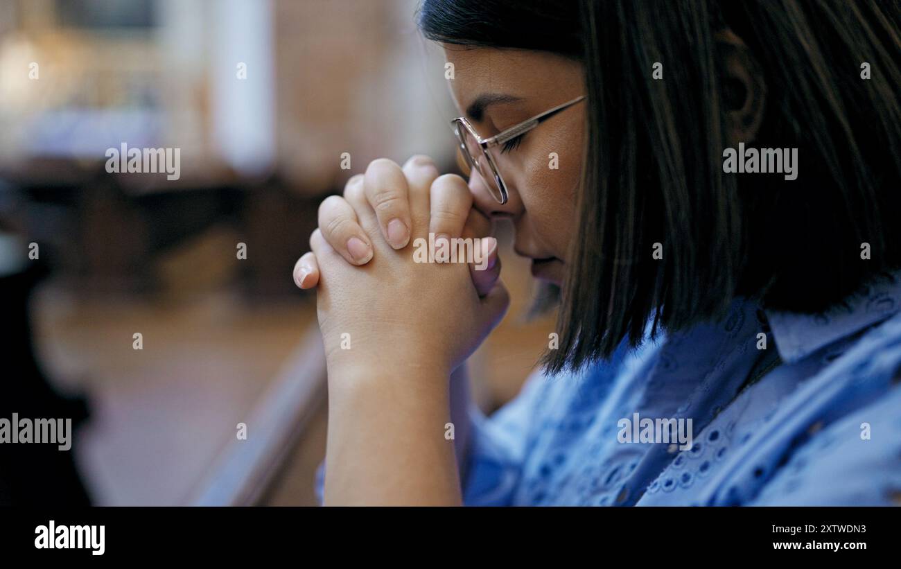 Young beautiful hispanic woman praying on a church bench at St. Karl ...