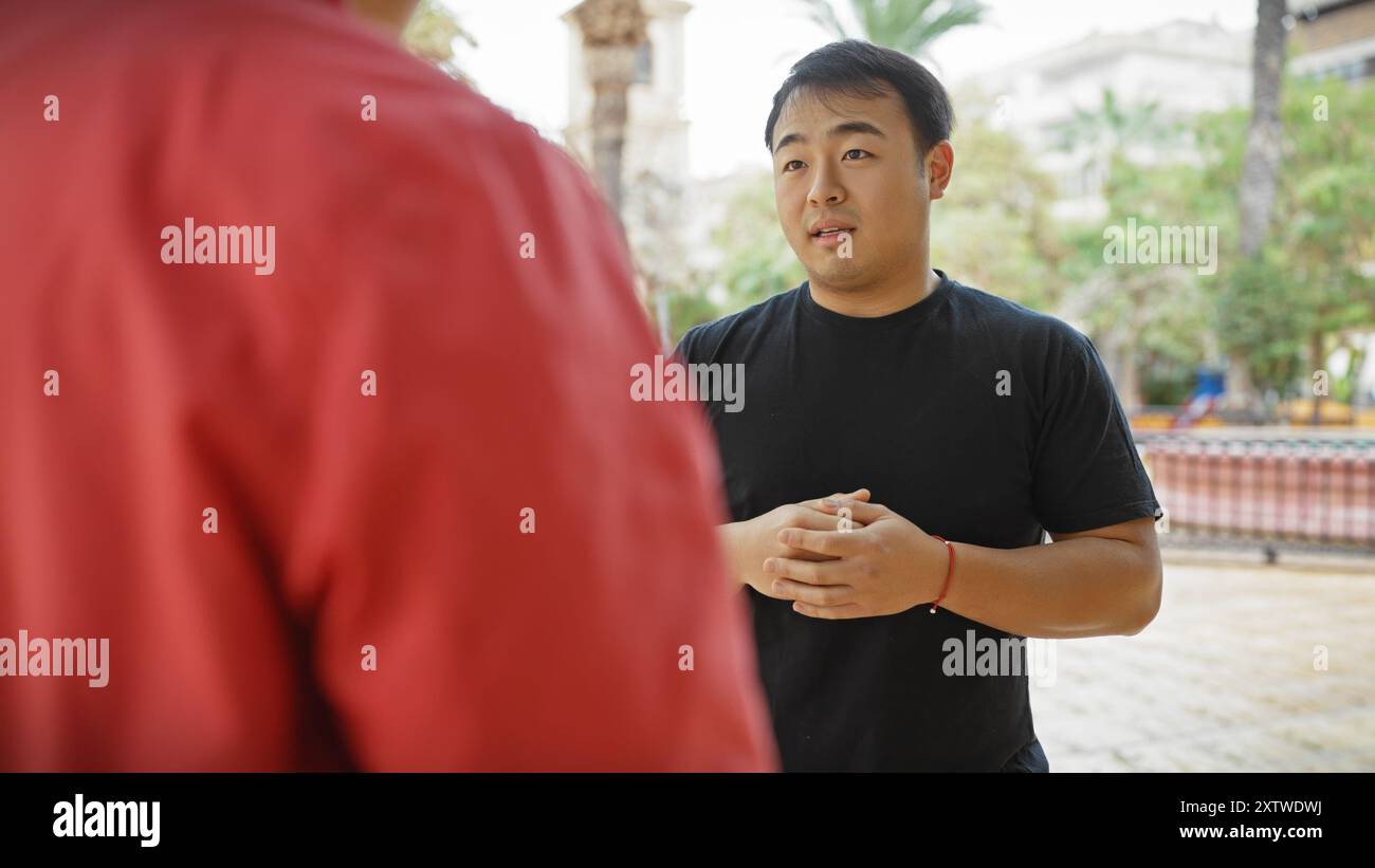 Two asian men casually conversing outdoors in a lush city park Stock ...