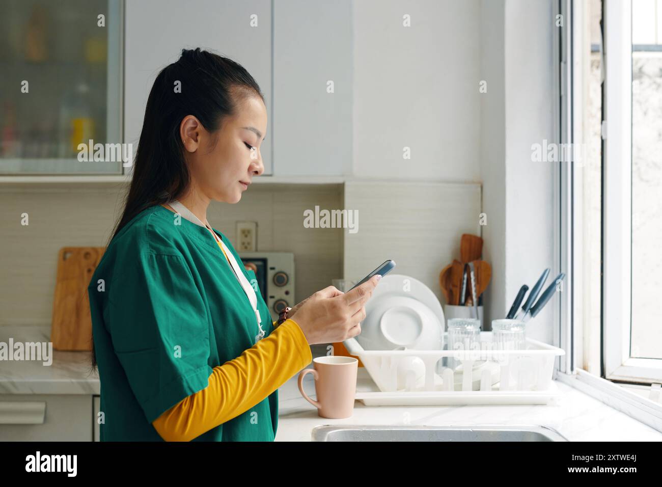 Checking Notifications in Modern Kitchen Setting Stock Photo - Alamy