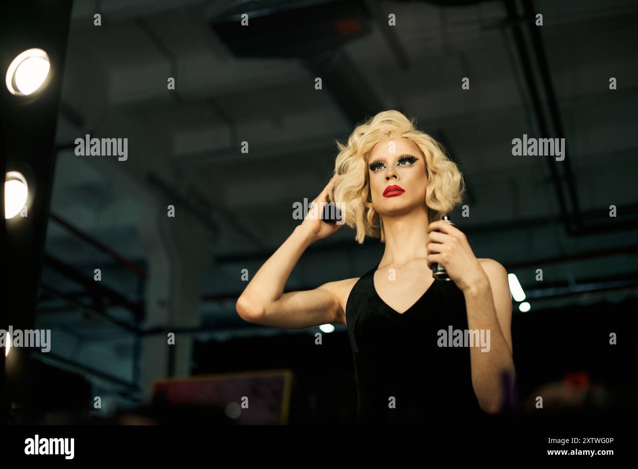 A drag queen adjusts their hair and makeup, preparing for a performance ...
