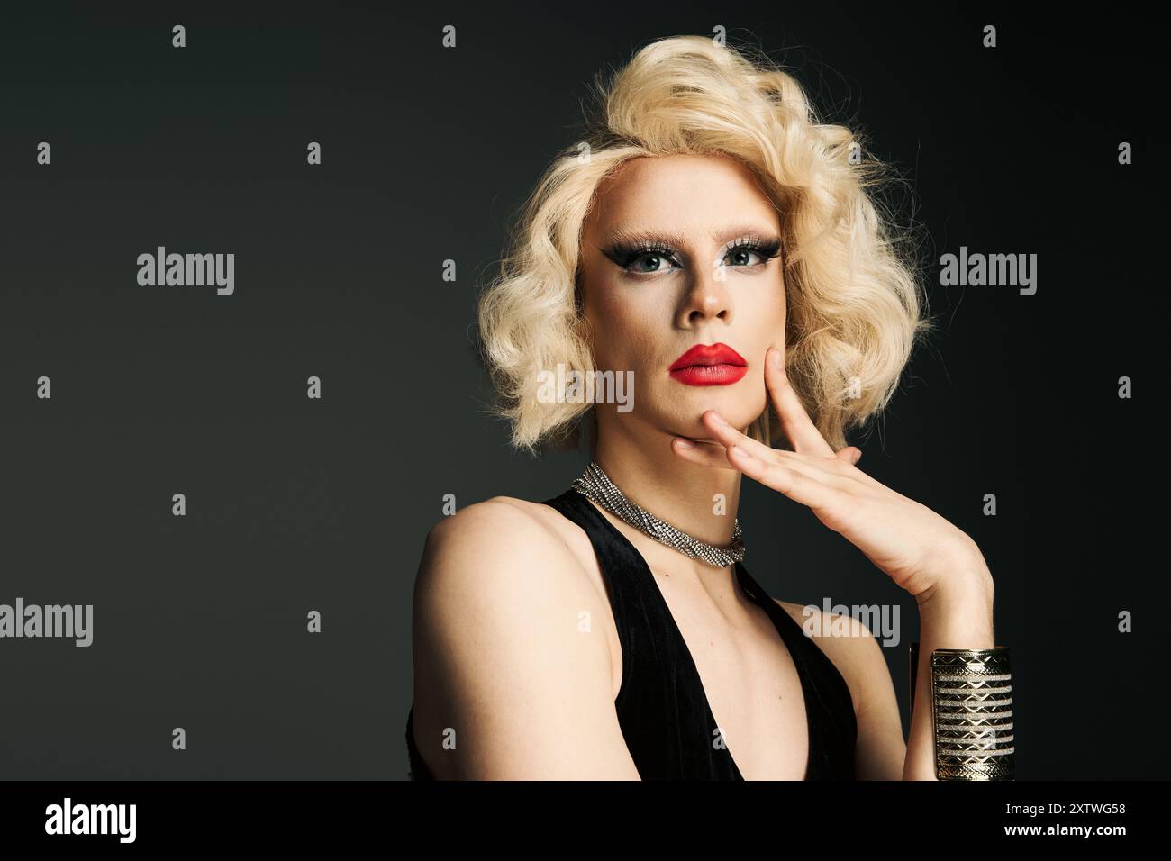 A drag queen with flawless makeup and a glamorous blonde wig poses in a ...