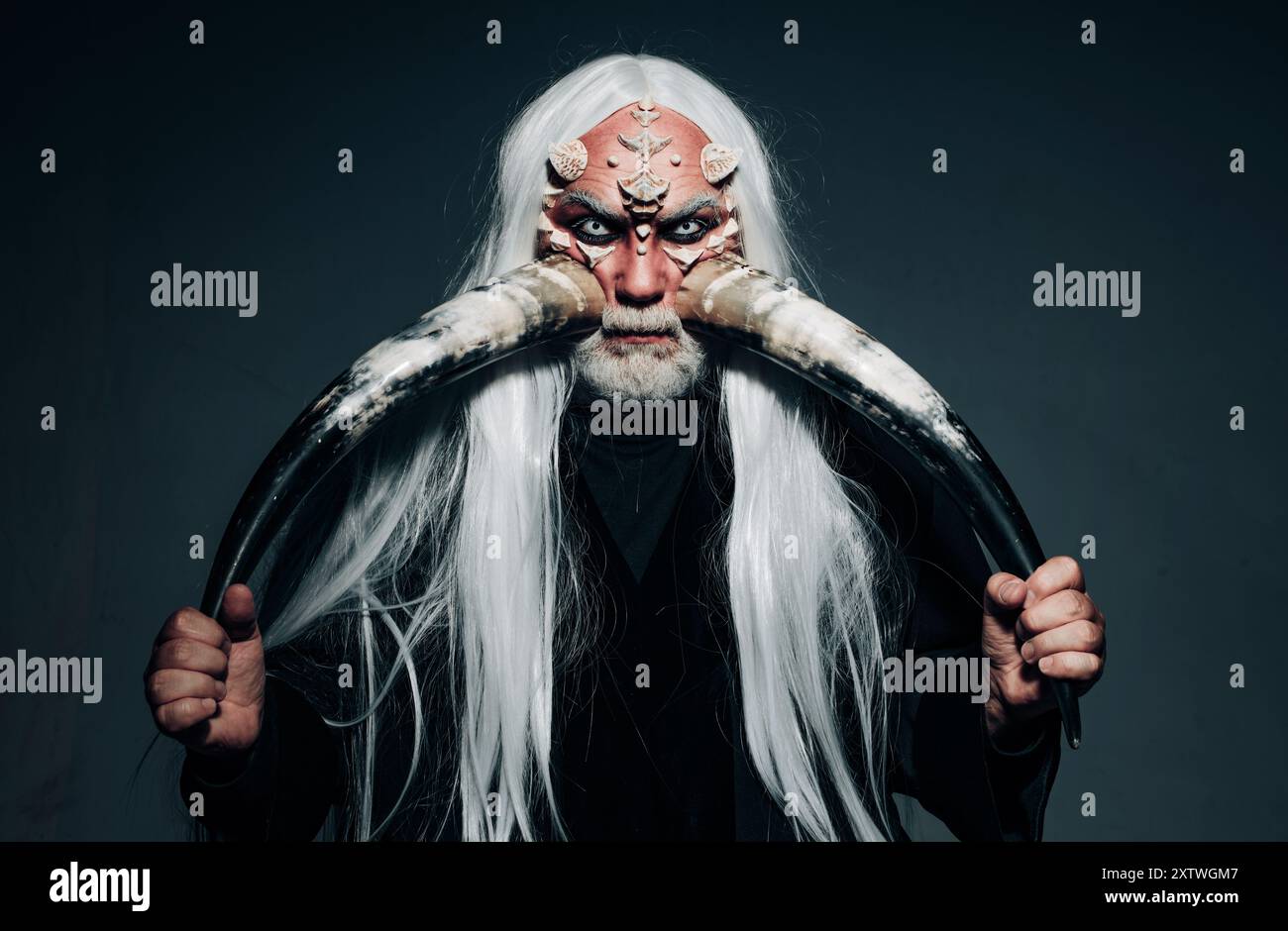 Elderly man holding two red horns. Demon head isolated on black ...