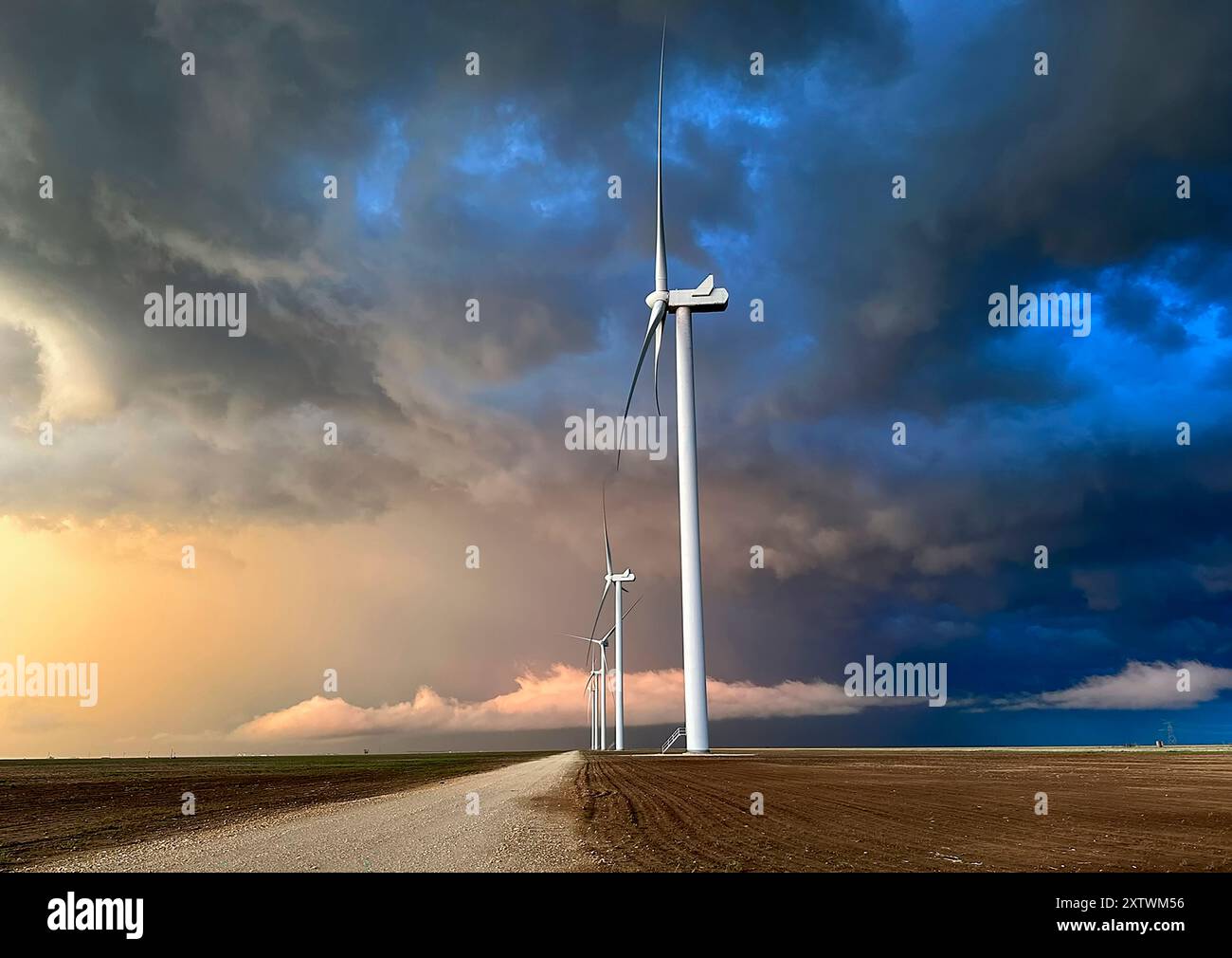 Sunset sky with storm clouds looming over a wind farm featuring two ...