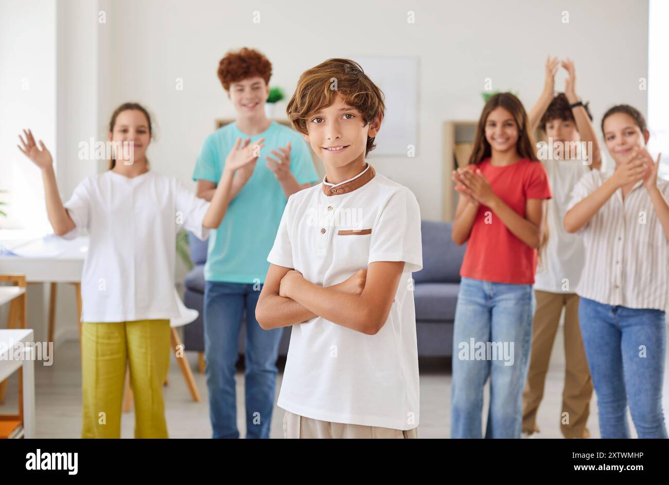 Teenage boy standing with crossed arms with friends or classmates ...