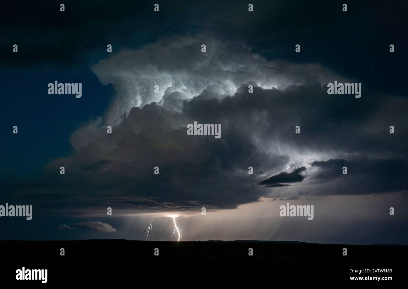 Lightning strikes illuminate a towering cumulonimbus cloud against the ...