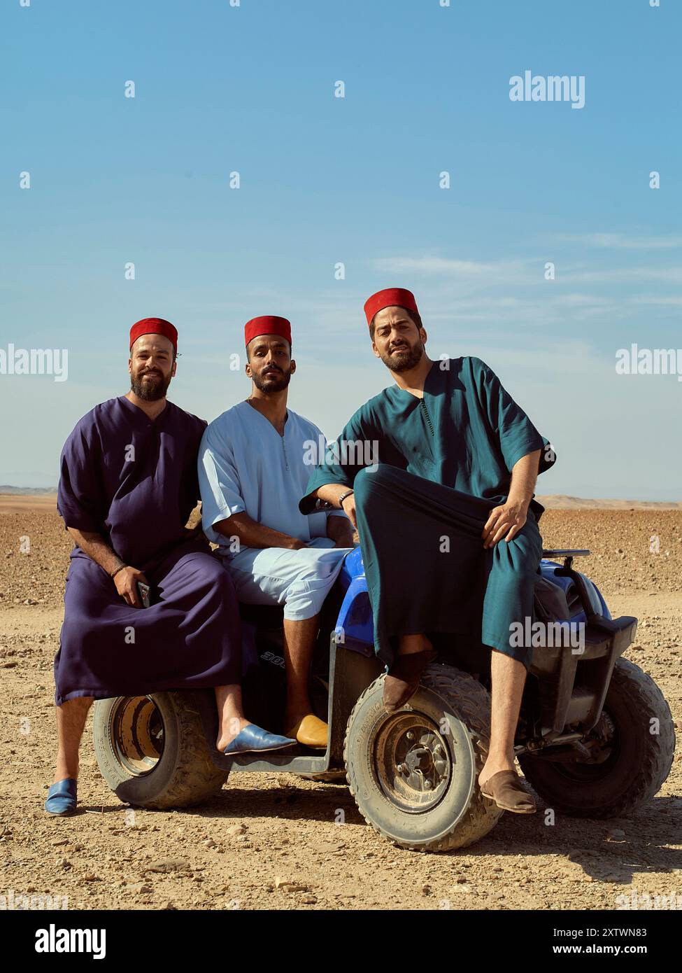 Three men wearing traditional fez hats pose confidently on a blue quad ...