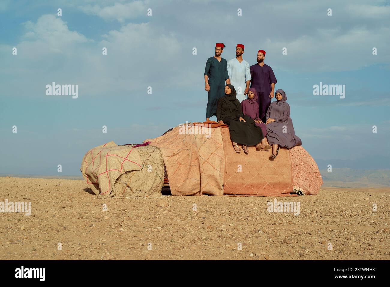 A group of seven people dressed in traditional attire posing on a rocky ...