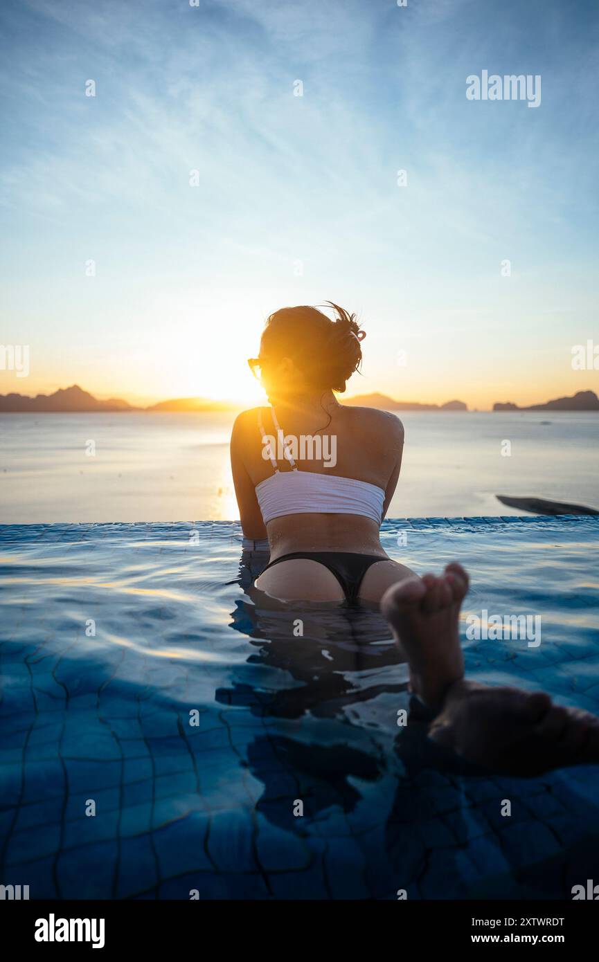 Sunset swimming pool relaxation with a woman enjoying the view Stock Photo - Alamy