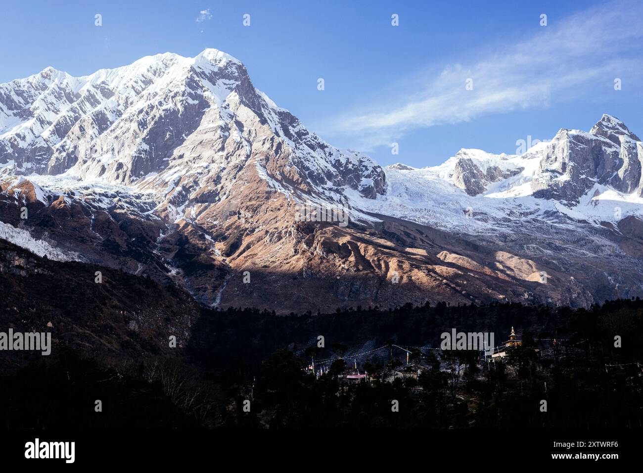 Snow-capped mountains rise majestically above a forested valley with a ...
