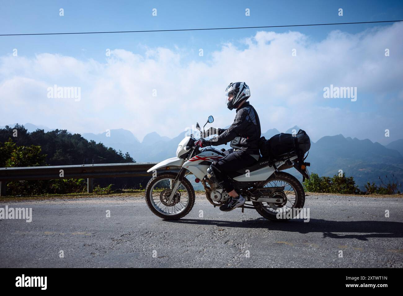 A motorcyclist in full gear rides a white adventure motorcycle on a ...