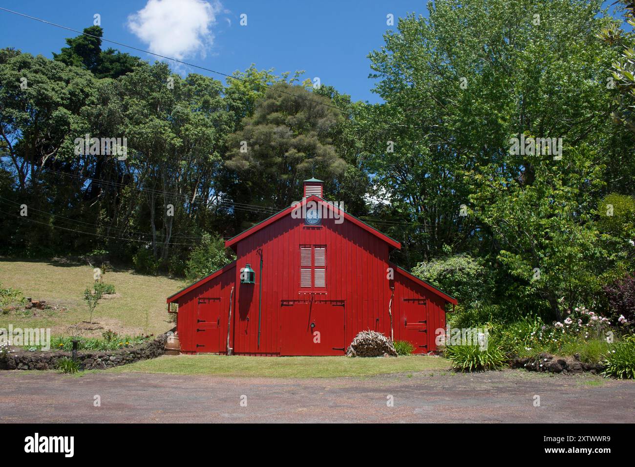 A bright red barn with white trimmings under a clear blue sky ...