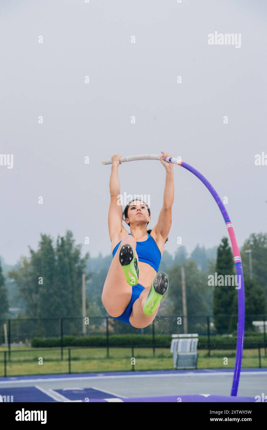 Female athlete performing a high jump over a bar at an outdoor track ...