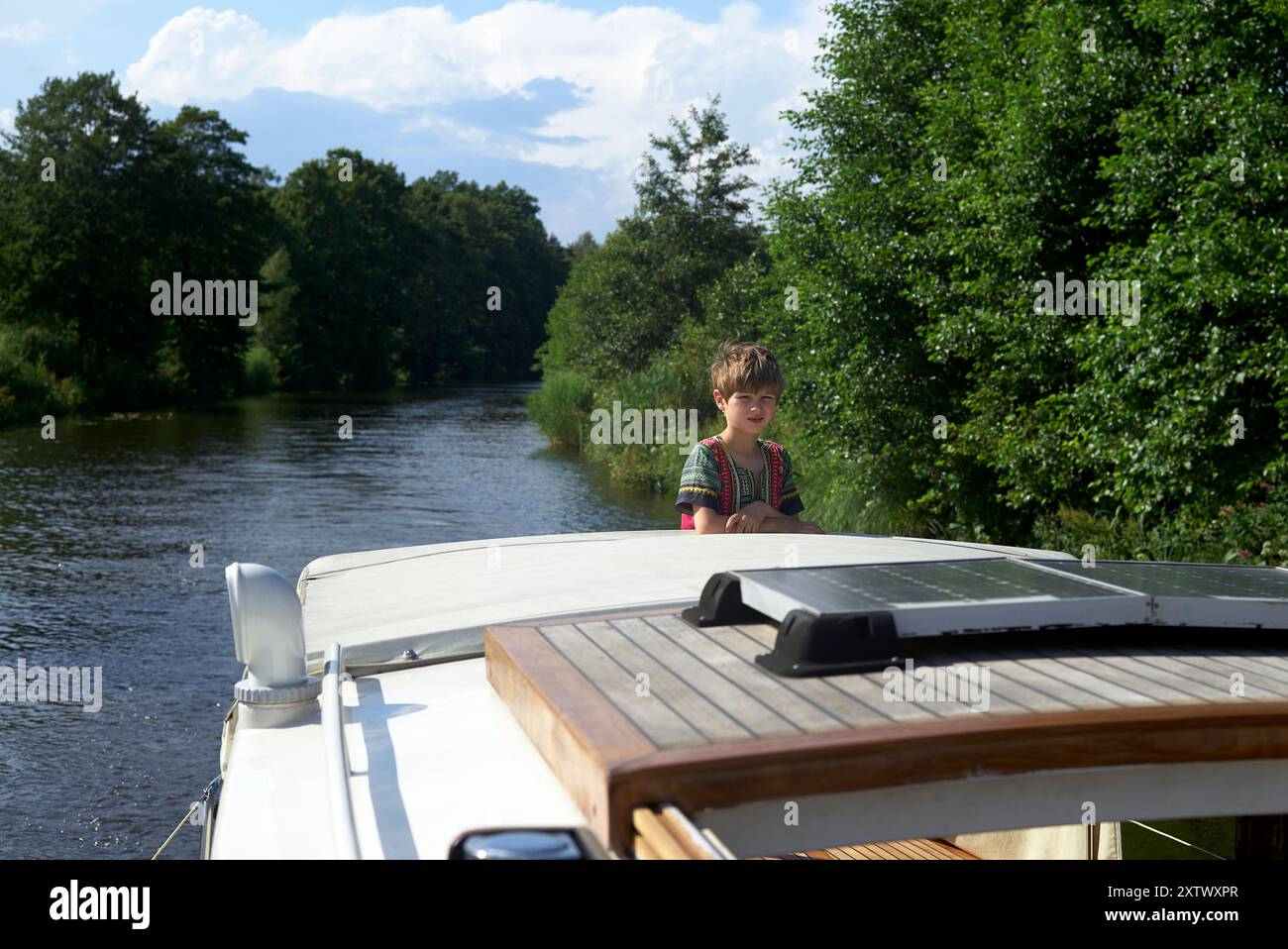 Child on a boat deck enjoying a sunny day on a scenic river cruise ...