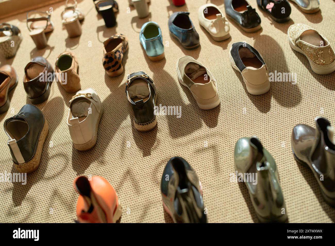 A diverse collection of shoes displayed on a beige background with ...