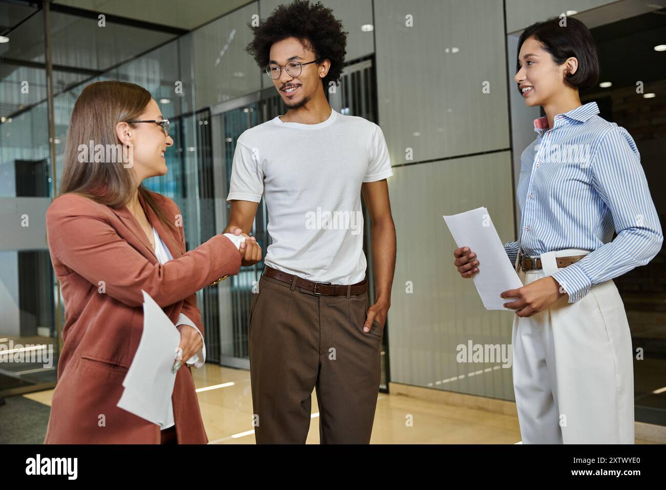 Colleagues chat in an office lobby, demonstrating diversity in the ...