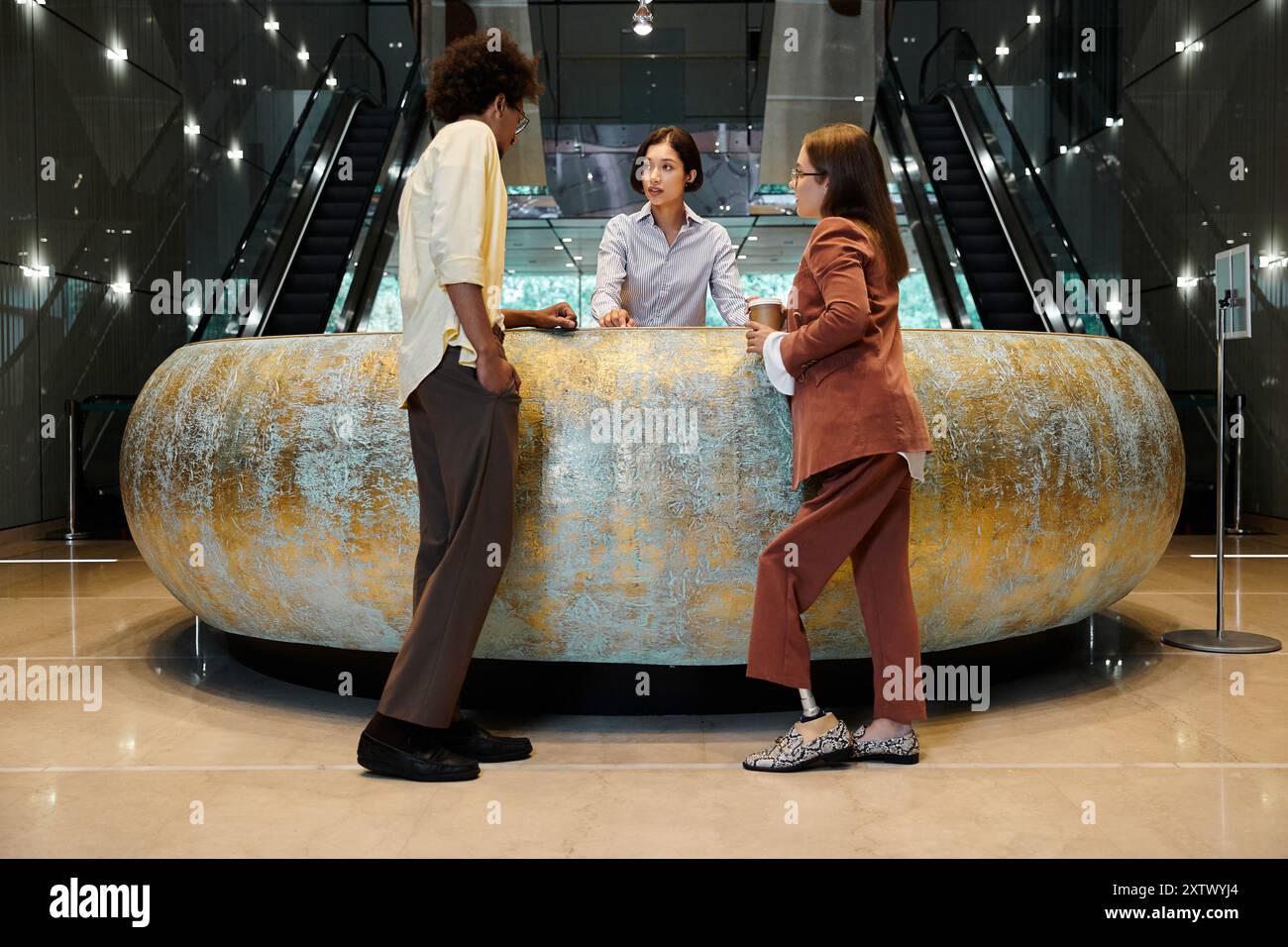 Three colleagues chat and enjoy coffee in a modern office lobby Stock ...