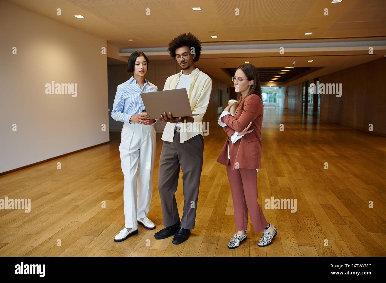 Three diverse colleagues converse in a modern office, showcasing ...