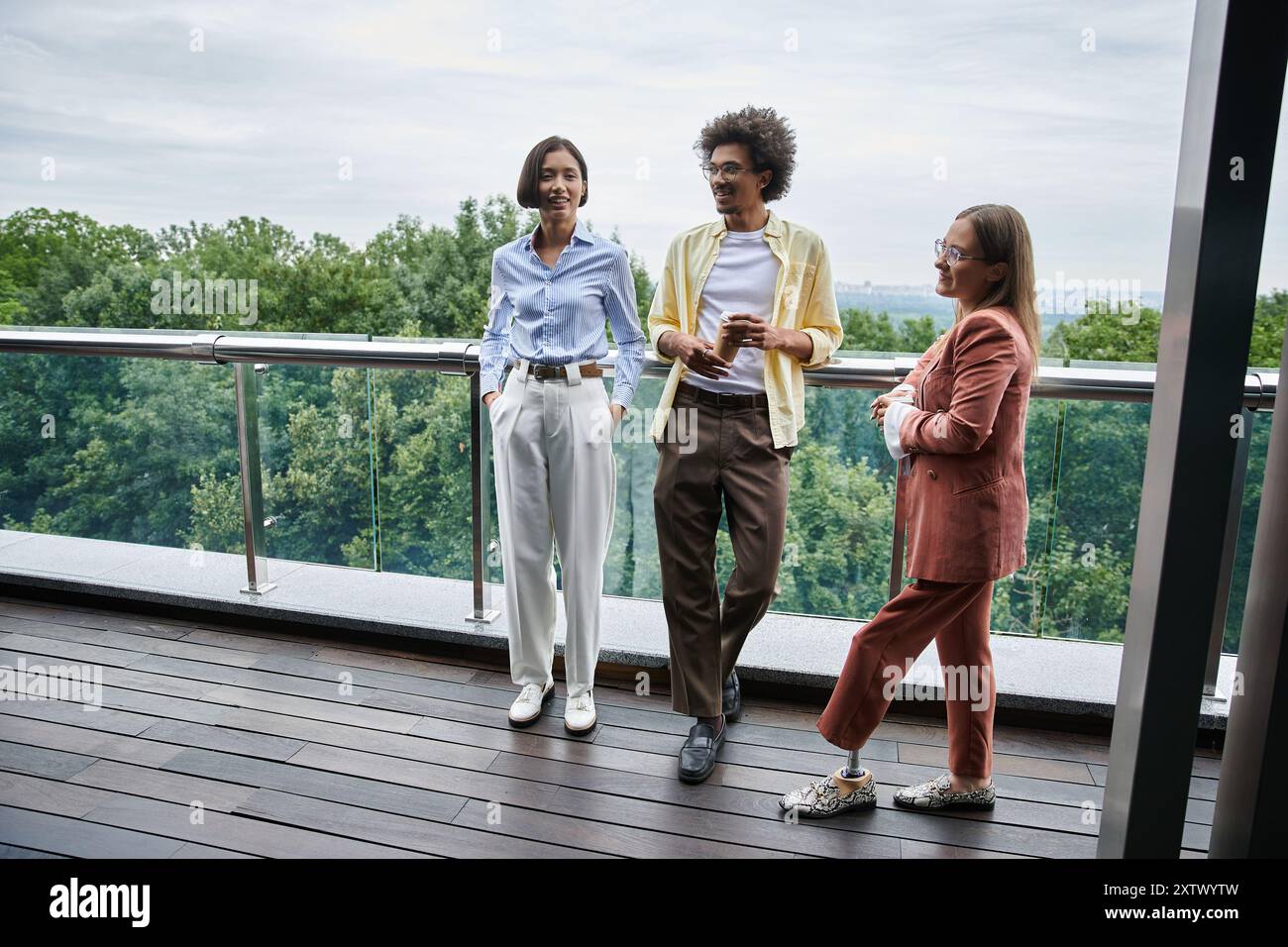 Three colleagues chat on a rooftop terrace, enjoying a break in their ...