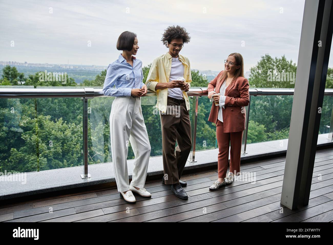 Three colleagues chat and laugh on a modern rooftop terrace Stock Photo ...