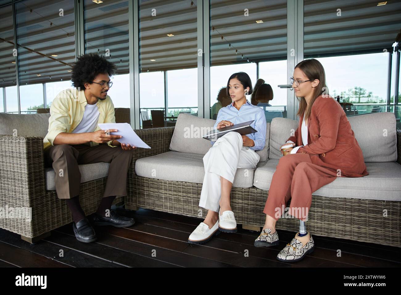 Three colleagues chat and work on a modern office rooftop terrace Stock ...