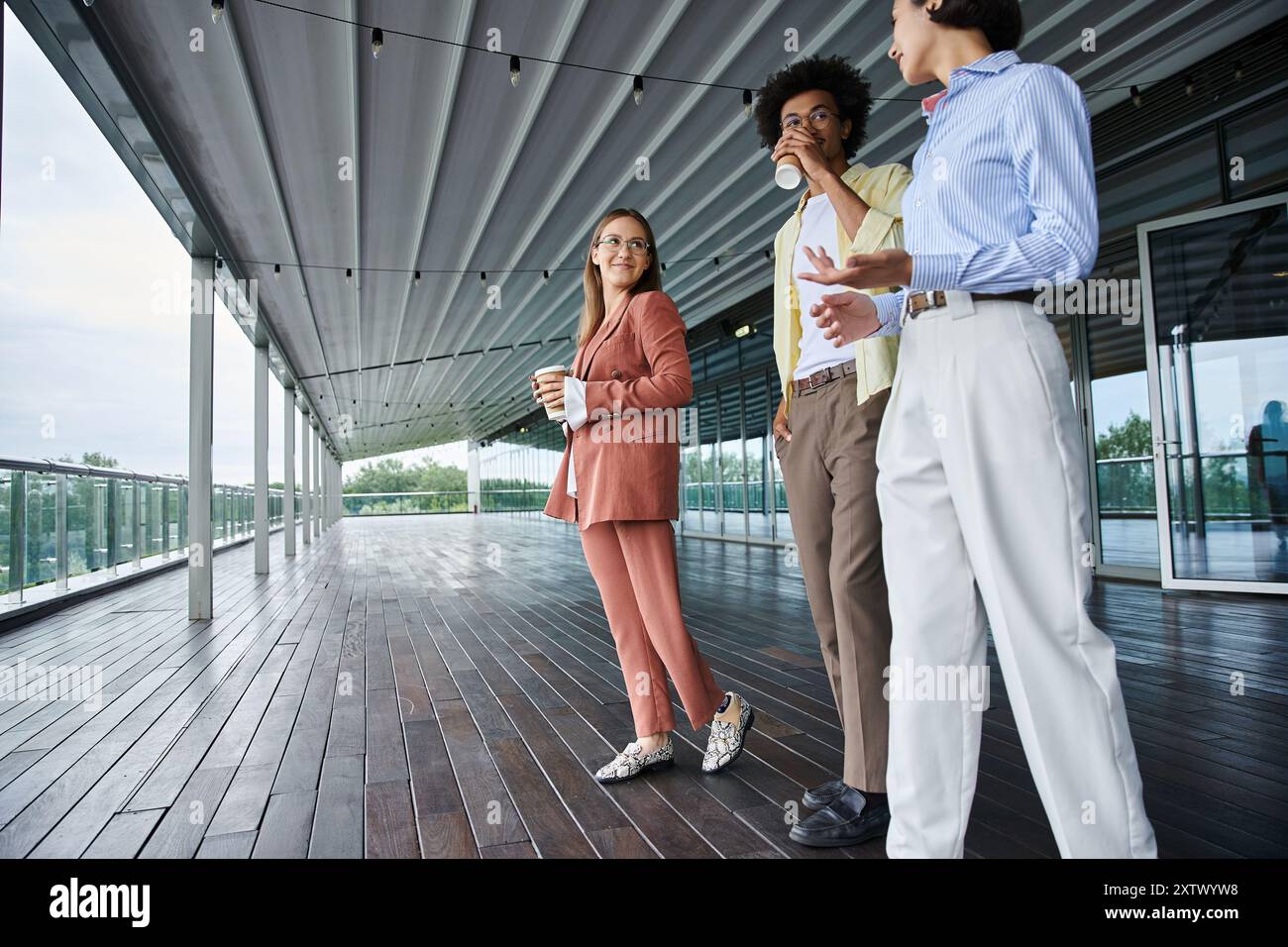 Three colleagues chat and walk on a modern office rooftop terrace Stock ...