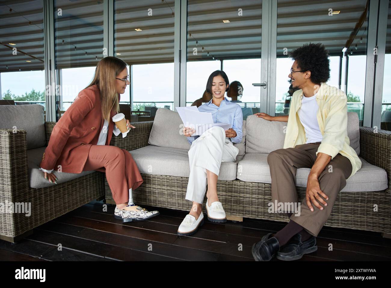 Three colleagues enjoy a relaxed conversation on a modern office ...