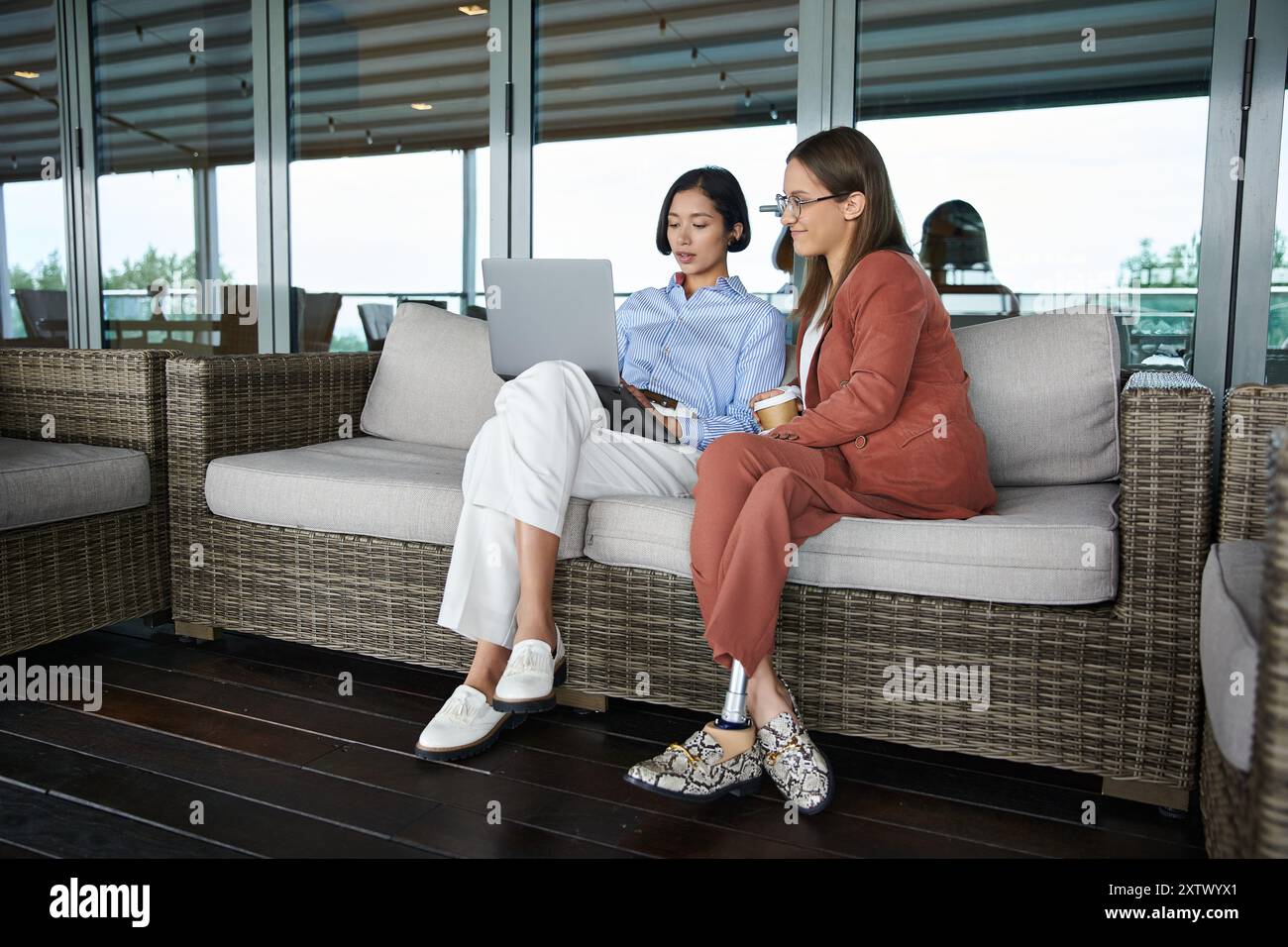 Two colleagues chat on a modern office rooftop terrace, one with a ...