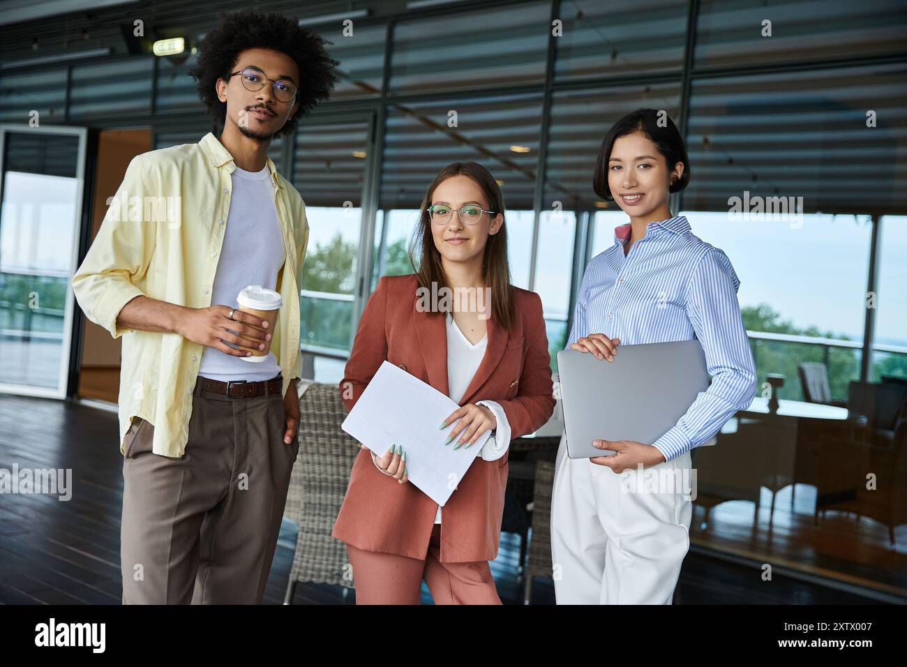 Three diverse colleagues chat and work on a rooftop terrace in a modern ...