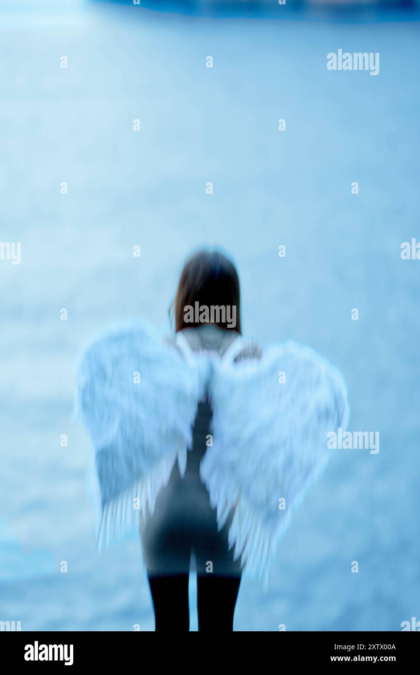 A blurred figure with angel wings stands facing away from the camera ...