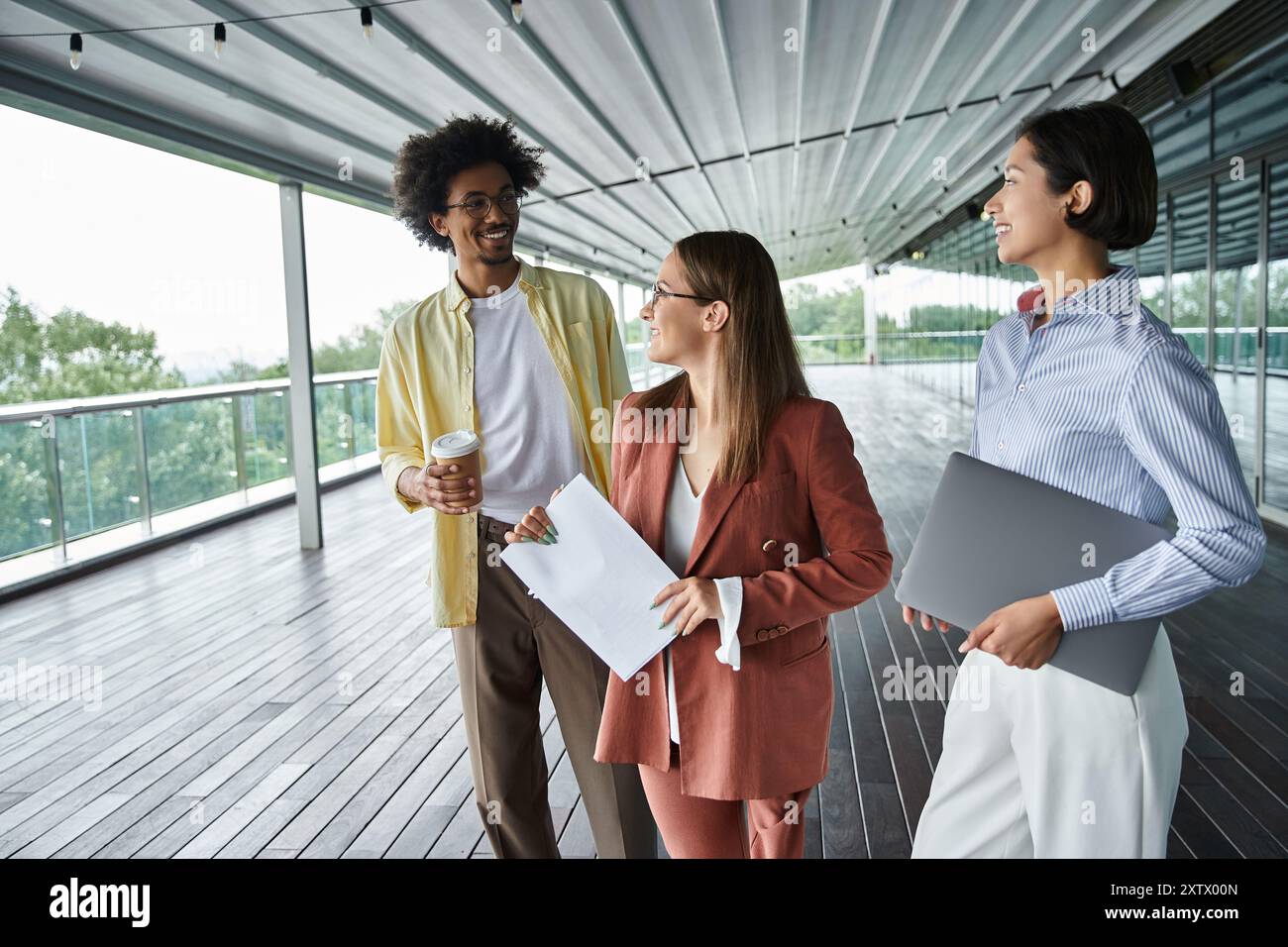 Three diverse colleagues chat and collaborate on a modern office ...