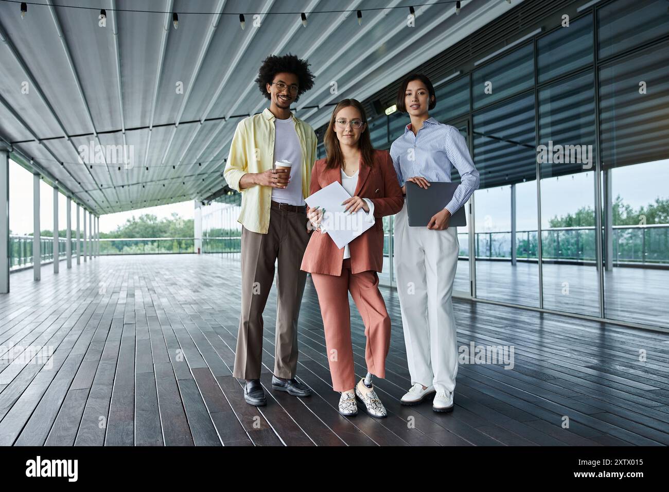 Three diverse colleagues chat and work on a rooftop terrace Stock Photo ...