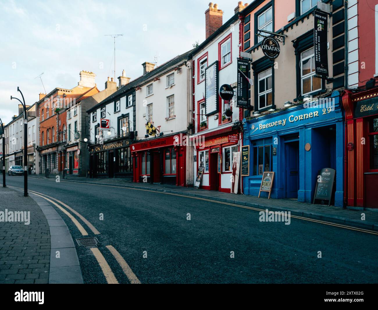 A peaceful street showcases a row of colorful pubs and shops, each with ...