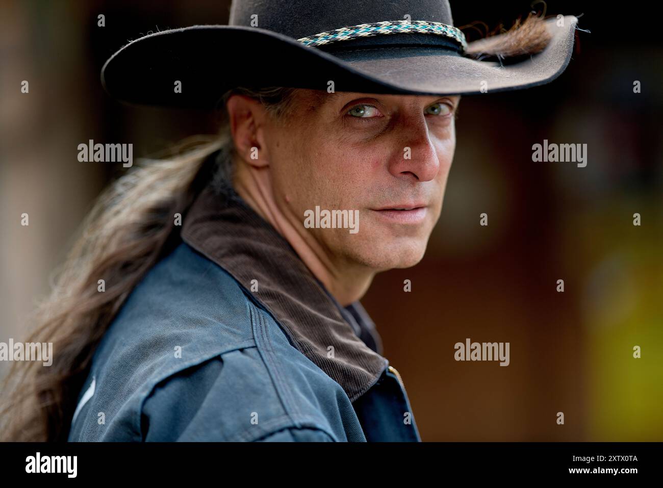 Close-up of a man with grey hair wearing a cowboy hat and looking over ...