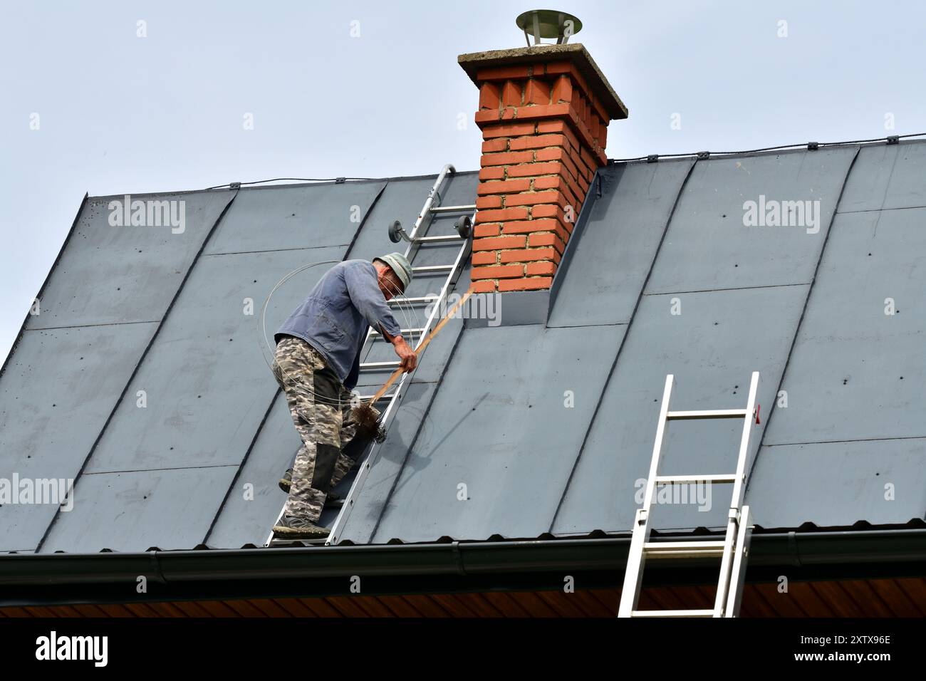 Traditional manual method of cleaning the chimney on the roof Stock ...