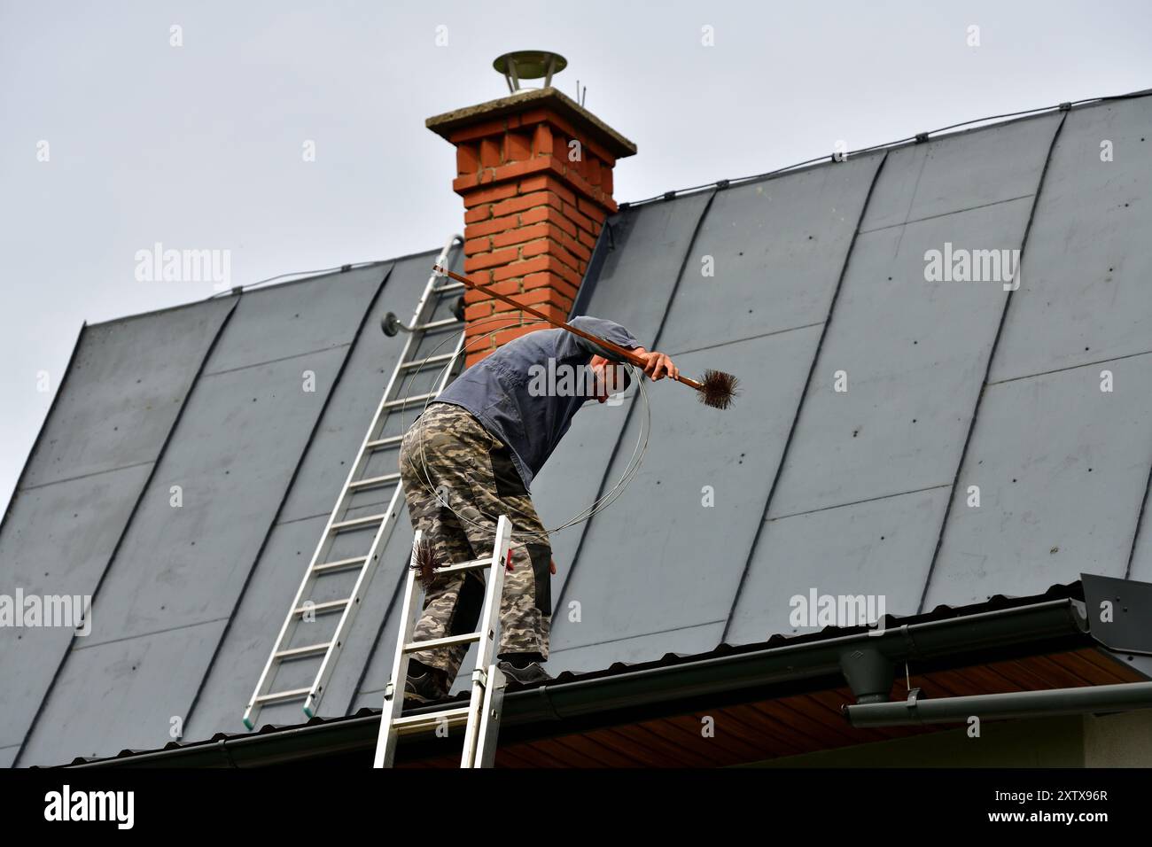 Traditional manual method of cleaning the chimney on the roof Stock ...