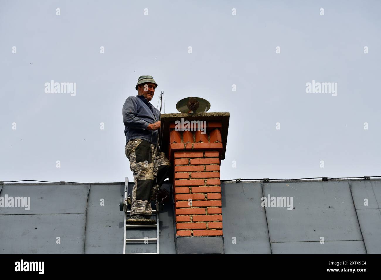 Traditional manual method of cleaning the chimney on the roof Stock ...