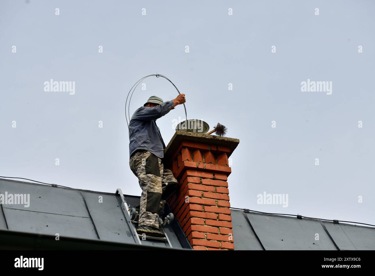 Traditional manual method of cleaning the chimney on the roof Stock ...