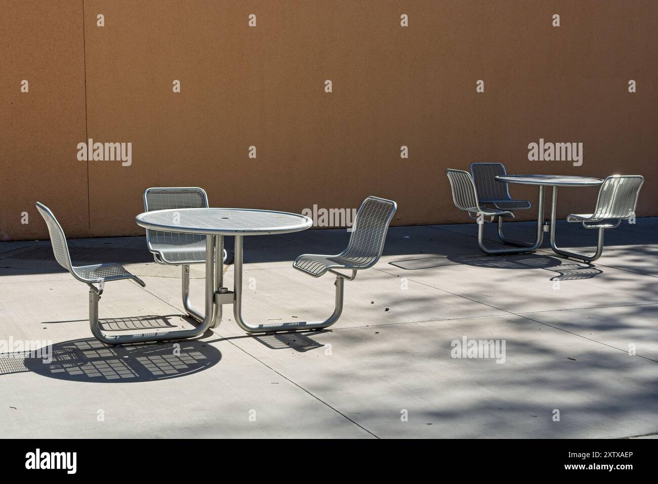 Two one-piece table and chairs on brightly lit concrete patio beside ...