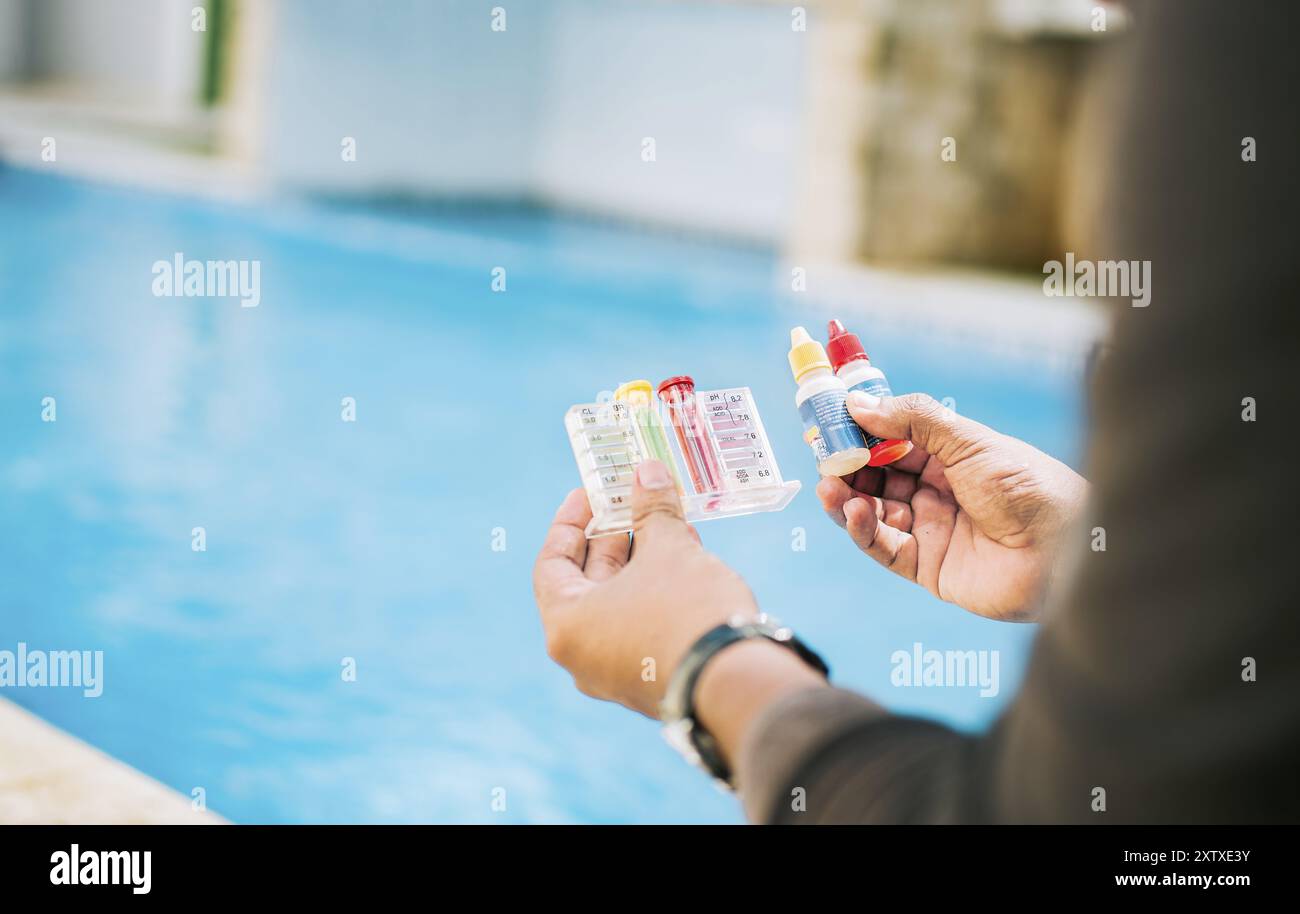 Person testing the PH of the swimming pool. Hand holding tester kit to ...
