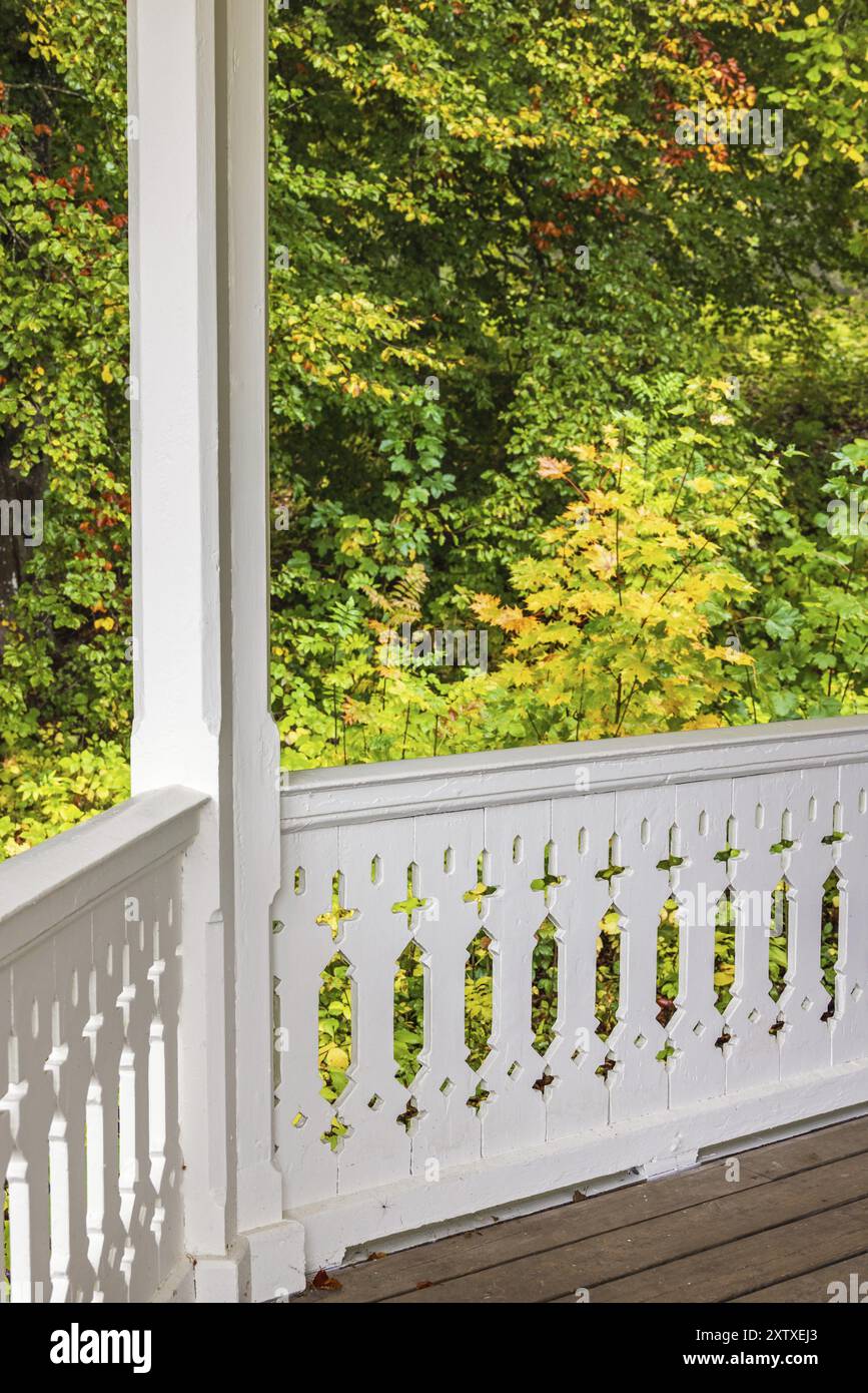 White wooden railing with joinery on a terrace with trees in autumn ...