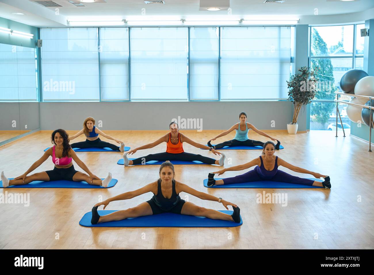 Womens health group performs stretching exercises in room with ...