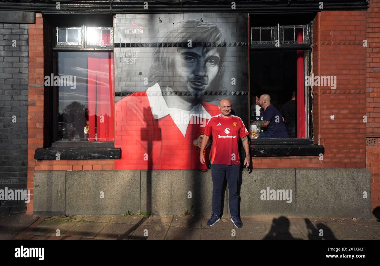 A Manchester United fan with a mural of former player George Best near ...