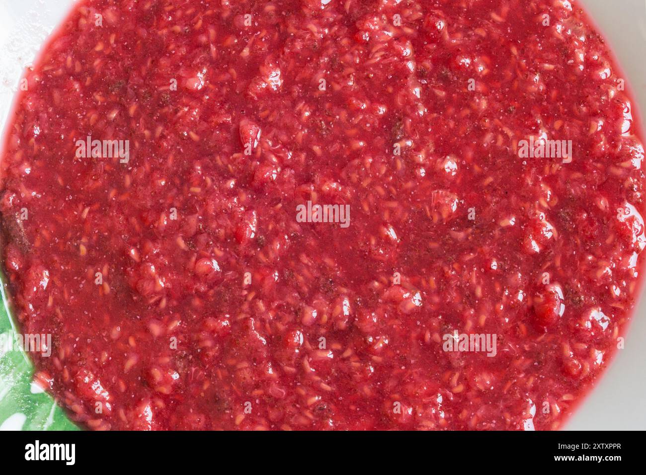 A close-up image showcases the rich texture of crushed raspberries on a ...