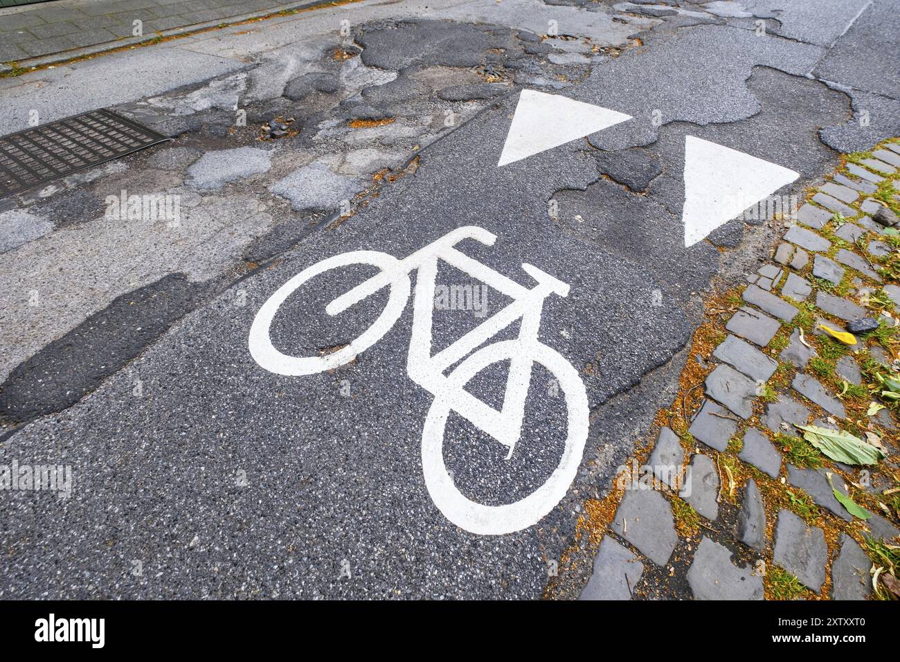 A cycle path pictogram on a road with potholes in Moenchengladbach ...