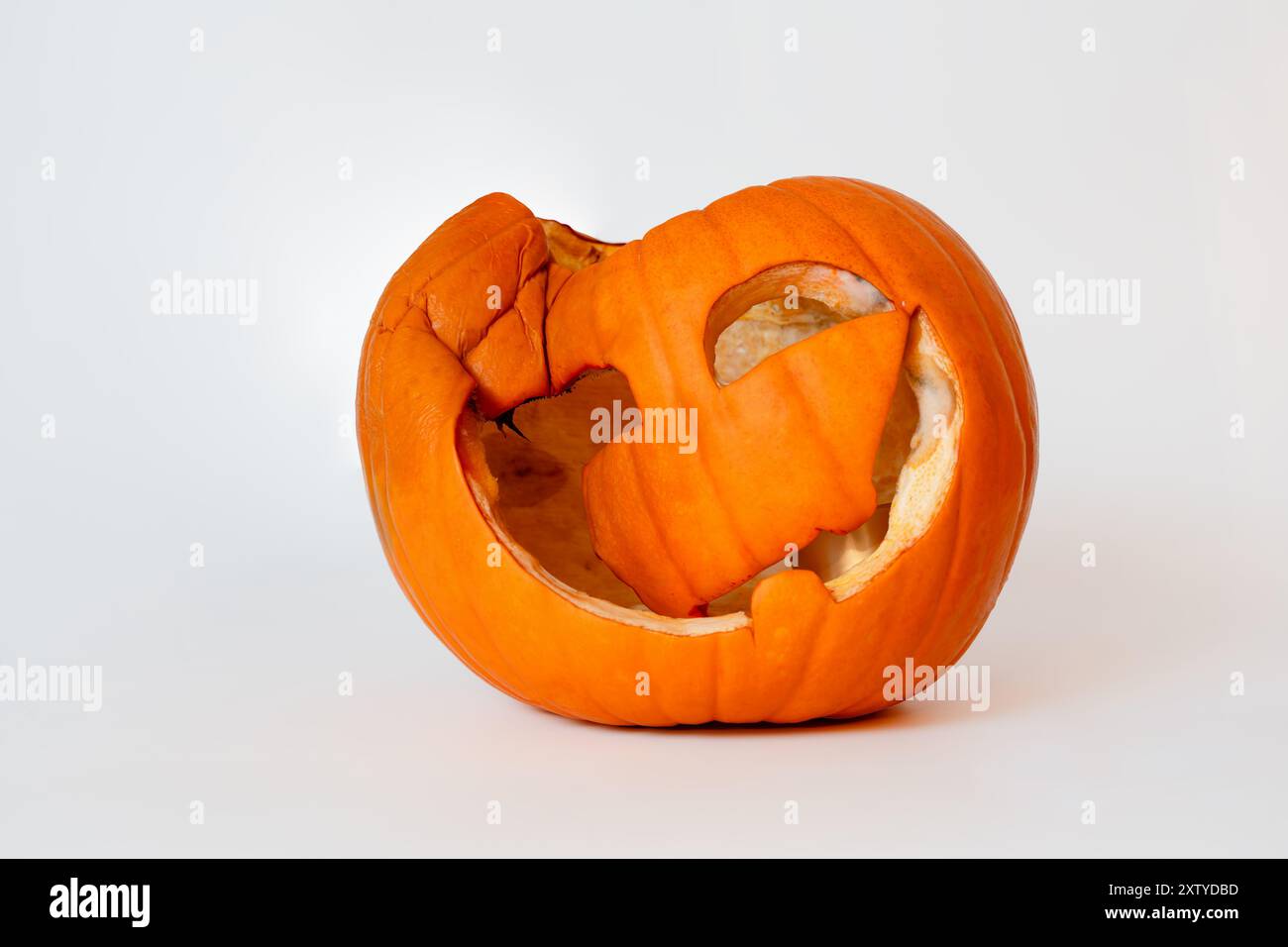 A collapsed and decayed Jack-o'-lantern with a broken face sits on a ...